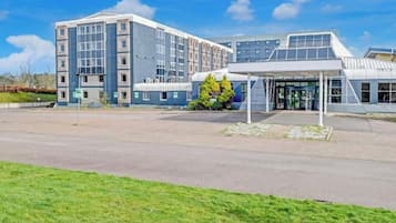 Um edifício moderno com entrada coberta, estacionamento e área gramada.