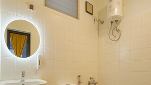 Um banheiro com pia branca, vaso sanitário e aquecedor de água instalado na parede.