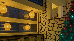 Um interior moderno com parede de pedra, árvore de Natal e várias luminárias pendentes.