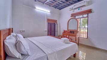 Quarto com cama, cadeira de madeira, janela com vista e ventilador de teto.