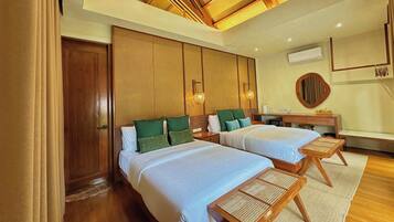 Quarto de hotel com duas camas, uma escrivaninha e um ventilador de teto.