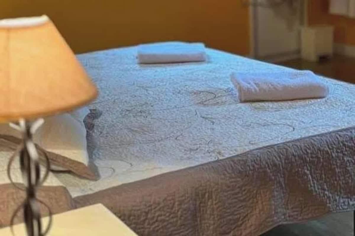 Quarto com cama, janela, pia e luminária.