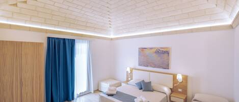 Quarto de hotel com teto em padrão de tijolos, uma cama grande com duas almofadas, uma mesa de cabeceira com abajur e um quadro na parede.