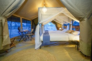 Tenda com cama, mesa e cadeira no interior.