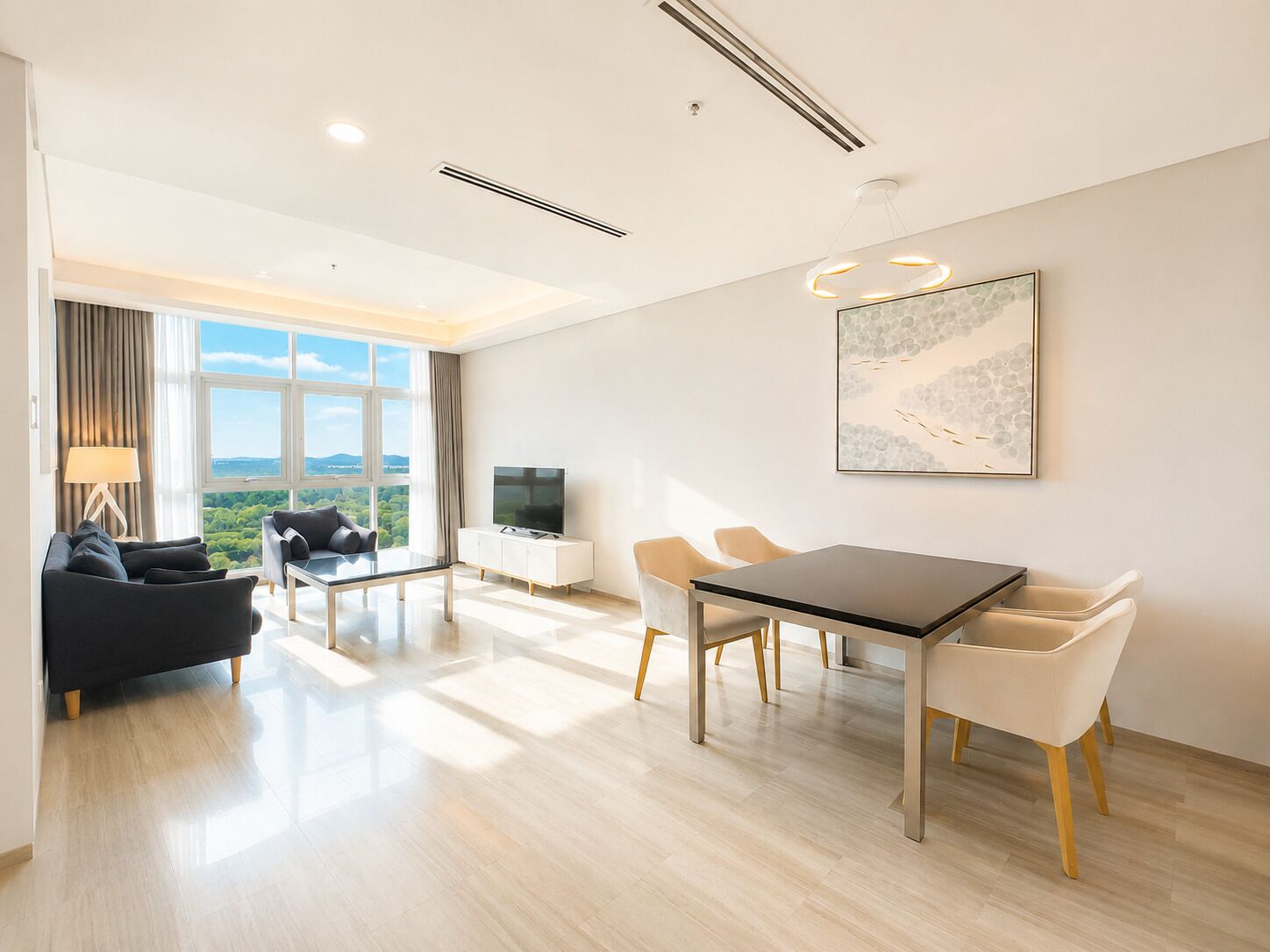 Quarto de hotel moderno com área de jantar, sofá, televisão e uma grande janela com vista panorâmica.