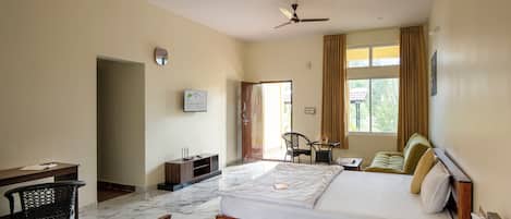 Quarto de hotel com duas camas, uma escrivaninha, uma cadeira e uma pequena mesa.