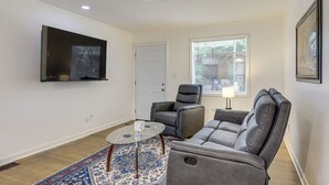 Uma sala de estar com sofá, poltrona e mesa de centro de vidro.