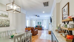 Uma sala de estar espaçosa com uma mesa de jantar, cadeiras, um sofá e um ventilador de teto.