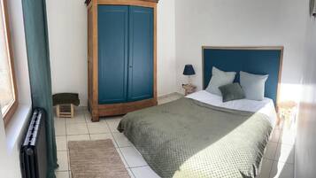 Quarto com cama, guarda-roupa de madeira, mesa de cabeceira e radiador.