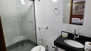 Um banheiro moderno com box de vidro, vaso sanitário, pia e espelho.