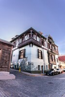 Um edifício histórico com estilo arquitetônico tradicional, destacando-se por uma varanda imponente e um mural na fachada.