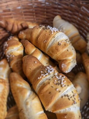 Uma cesta com pães recém-assados, cobertos de sementes de gergelim e ervas.
