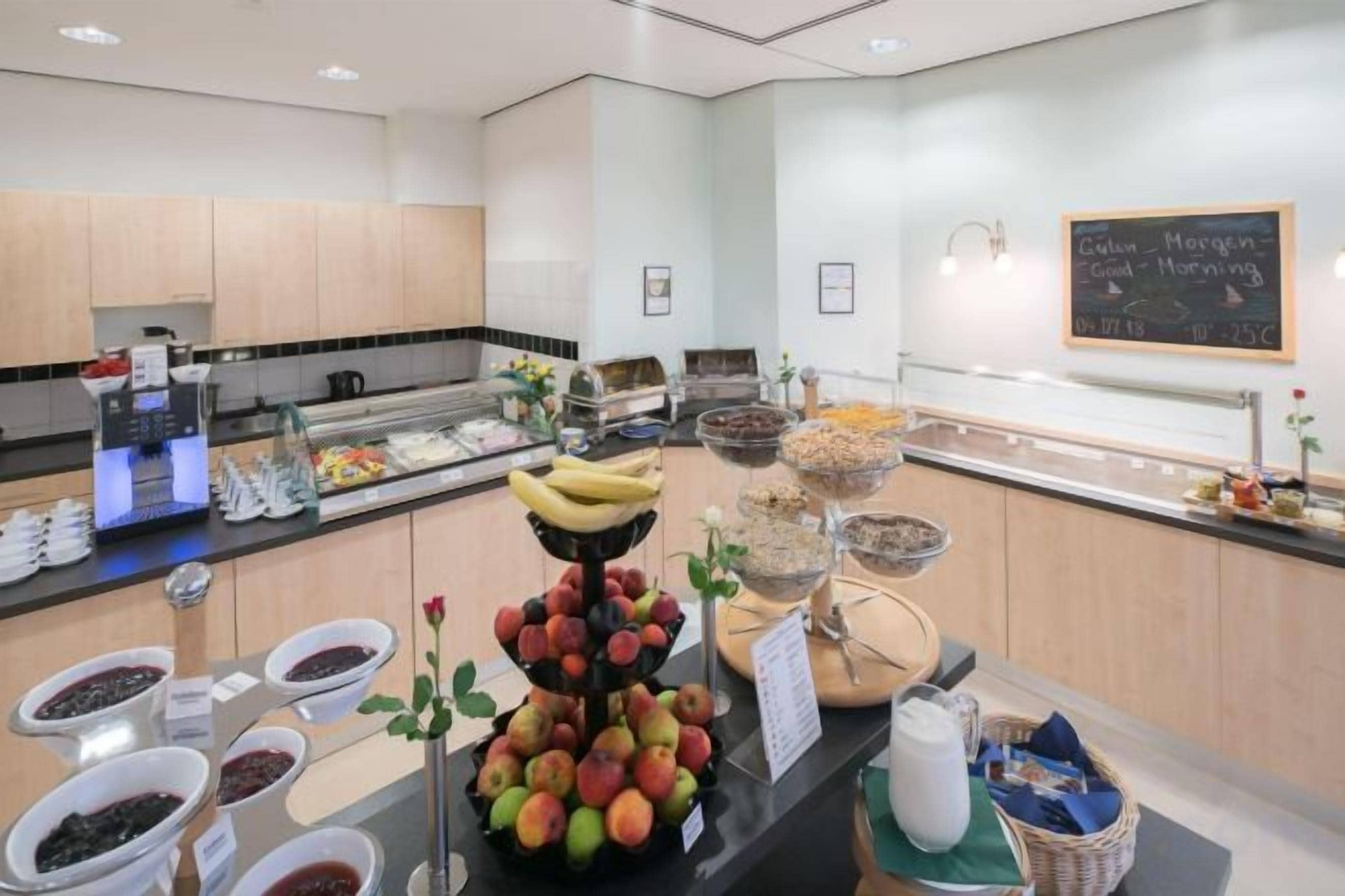 Buffet de café da manhã com diversos alimentos e uma máquina de café.