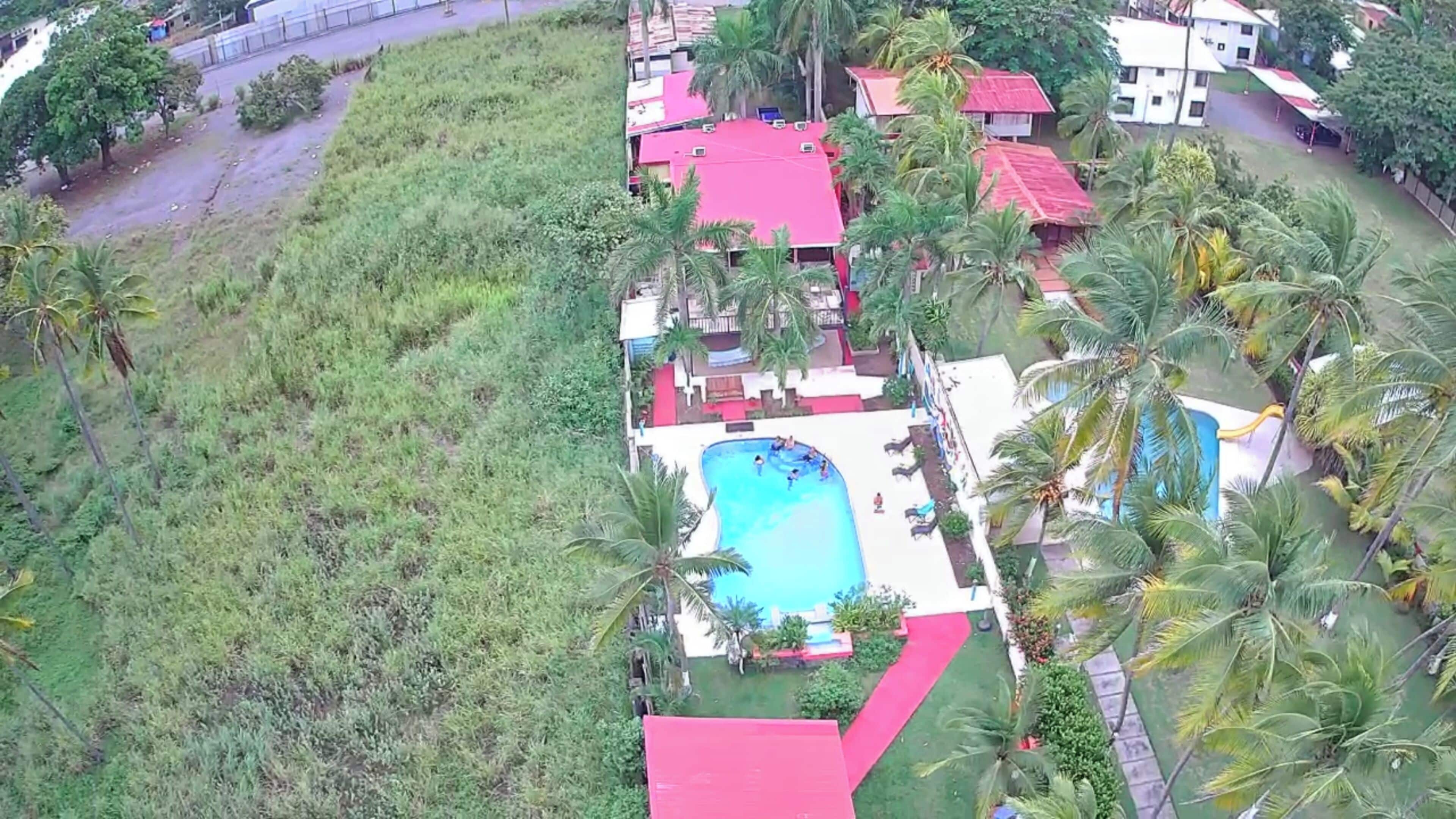 Um bairro residencial com piscina, palmeiras e casas com telhados vermelhos.