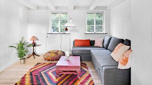 Uma sala de estar moderna com um sofá cinzento, um tapete colorido e uma mesa de centro de madeira.
