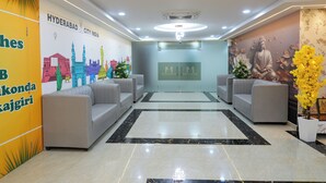 Um saguão de hotel com sofás, uma mesa de recepção e uma estátua de Buda.