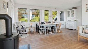 Quarto acolhedor com área de jantar, lareira e grandes janelas com vista para o exterior.