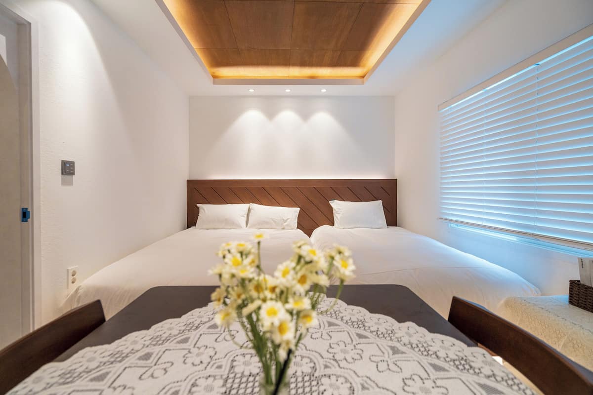 Quarto moderno com teto de madeira, uma cama grande com roupa de cama branca e uma mesa de cabeceira com um vaso de flores.