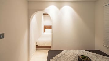 Quarto com uma cama, mesa de cabeceira com um objeto decorativo e janela com persianas.