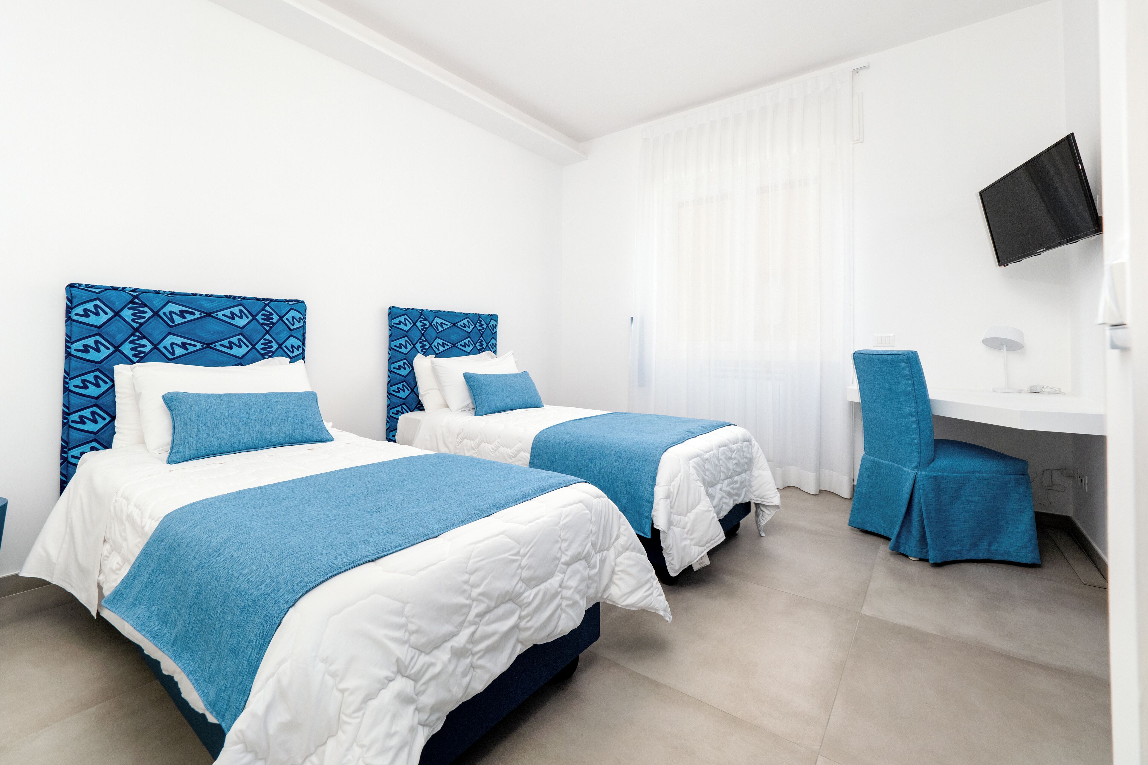 Quarto de hotel com duas camas, uma escrivaninha e uma televisão.