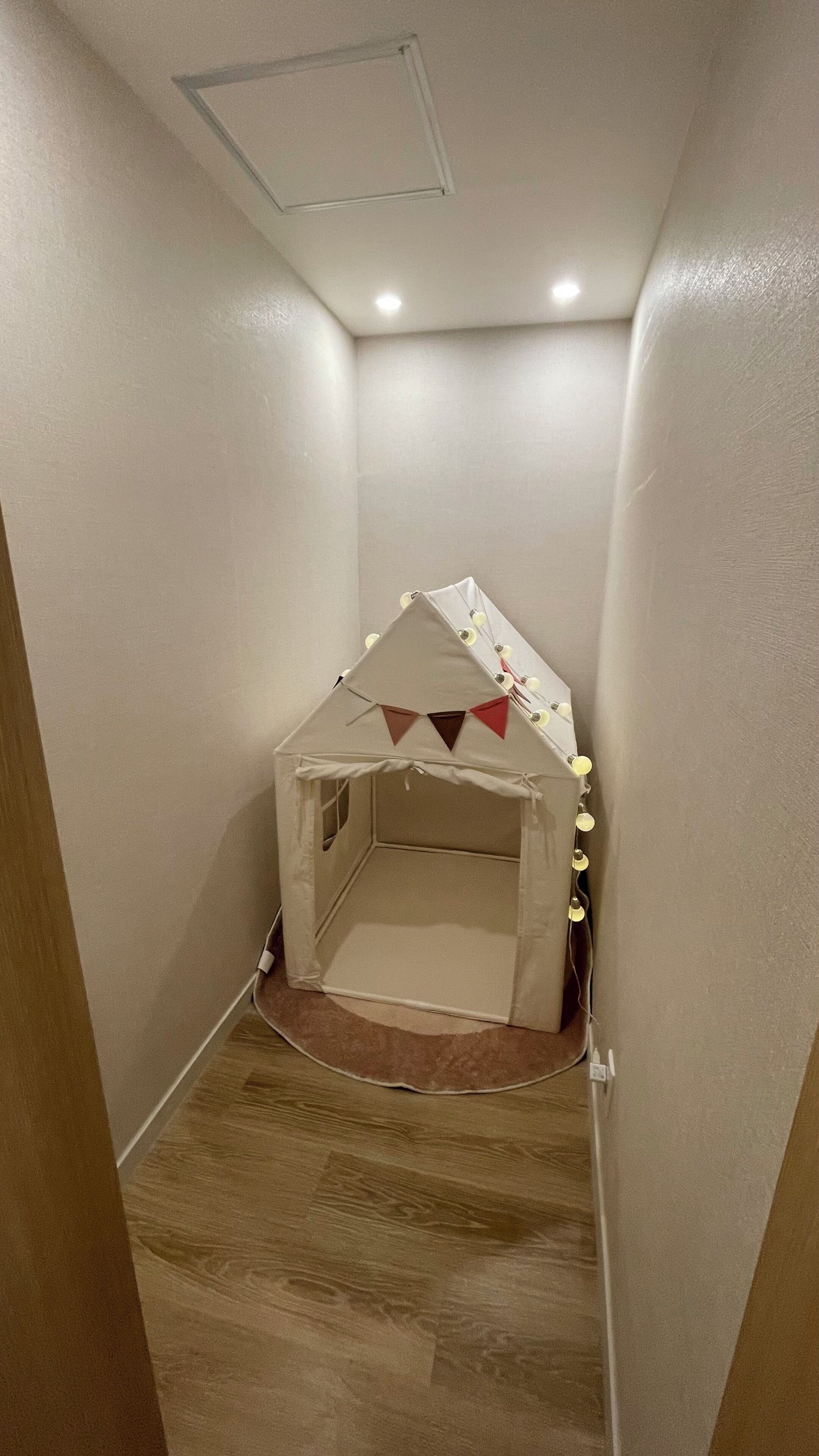 Um corredor estreito com uma casinha de brincar no final.