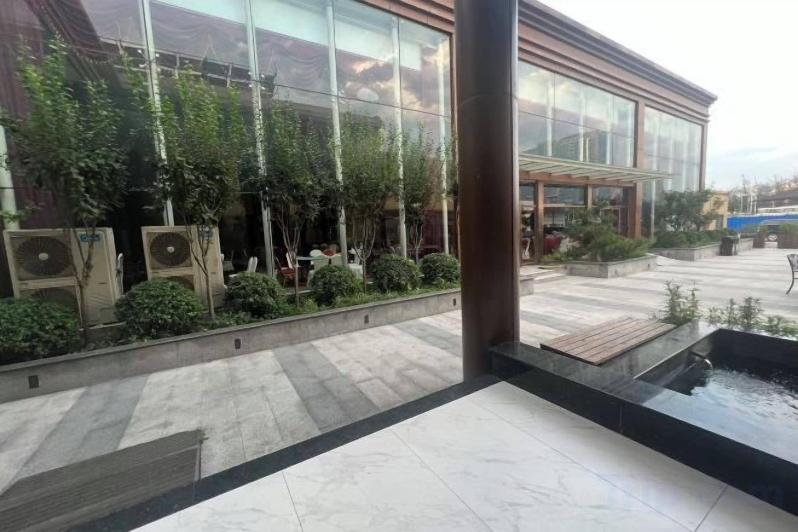 Um edifício moderno com grandes janelas, área de estar ao ar livre e um espelho d'água.
