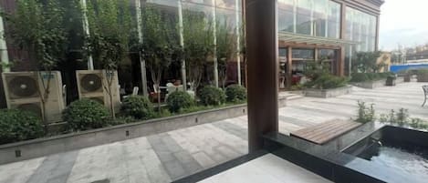 Um edifício moderno com grandes janelas, área de estar ao ar livre e um espelho d'água.