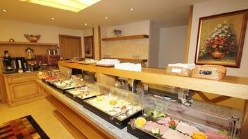 Uma área de buffet com diversas opções de comida, um balcão de madeira e um quadro na parede.