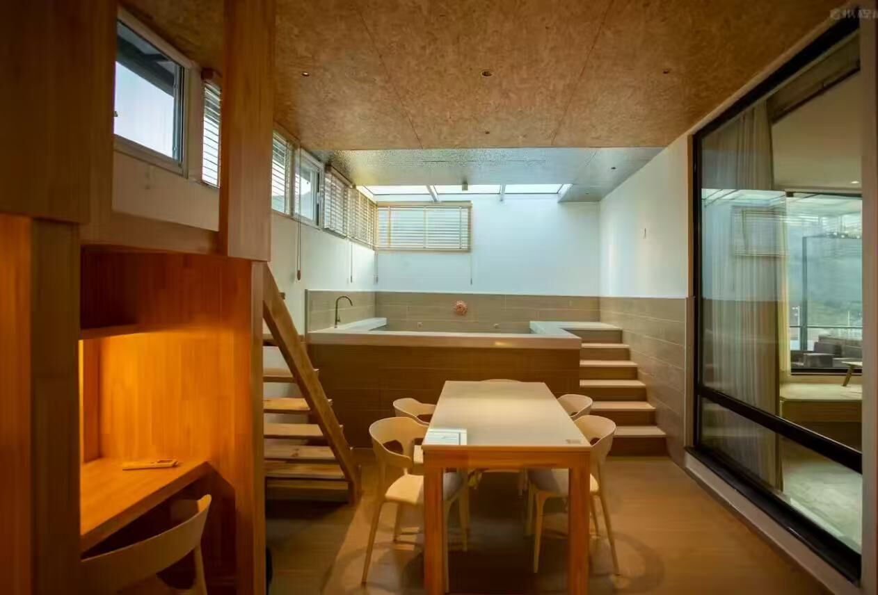 Um banheiro moderno com banheira, uma mesa de madeira e cadeiras, além de uma janela grande.