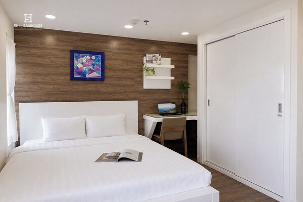 Quarto de hotel moderno com uma cama grande, uma mesa e um guarda-roupa.