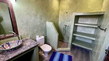 Casa de banho com lavatório de mármore, sanita e chuveiro com porta de vidro.