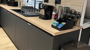 Uma cozinha moderna com máquina de café embutida, espaço para café e lixeira.