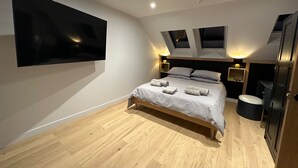 Quarto moderno com uma cama grande, uma TV de tela plana na parede e claraboias.