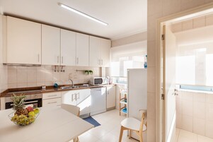 Uma cozinha moderna com armários brancos, micro-ondas e um espaço de refeições com mesa e cadeiras.