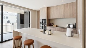 Uma cozinha moderna com uma ilha grande, banquetas e vista para a cidade.