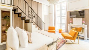 Uma sala de estar moderna com escada, um sofá, uma poltrona laranja e uma lareira.