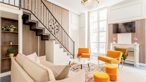Uma sala de estar moderna com escada, um sofá, pufes, uma mesa de centro e uma lareira.