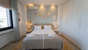 Quarto de hotel com uma cama grande, duas mesas de cabeceira com abajures, uma janela com cortinas e um guarda-roupa.