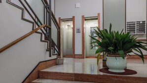 Escada com revestimento em mármore, um vaso de planta e guarda-corpo de metal.