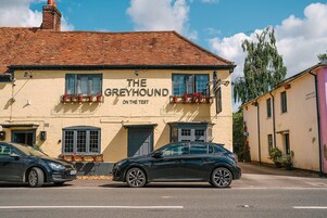 Um edifício com a placa 'The Greyhound On The Test' e um carro estacionado em frente.