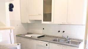Cozinha com armários brancos, máquina de lavar louça Bosch, bancada de granito e pia de aço inoxidável.