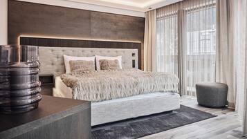 Quarto moderno com uma cama grande, mesa de cabeceira e uma janela ampla com cortinas.