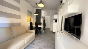 Uma sala de estar moderna com sofá, mesa de jantar, cadeiras e televisão.