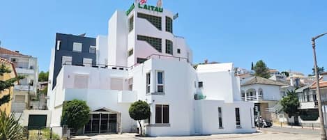 Um hotel moderno com fachada branca, uma placa em destaque e uma bandeira.