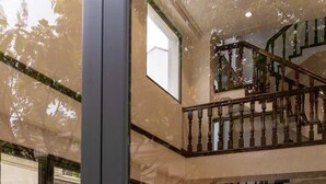 Uma sala de estar ampla e elegantemente decorada, com teto alto, uma escadaria imponente e vista para o exterior.