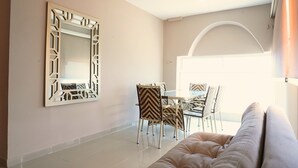 Uma sala de jantar moderna com um espelho geométrico, cadeiras de vime e um sofá acolchoado.