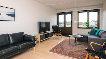 Uma sala de estar moderna com televisão de tela plana, sofás de couro, uma mesa de centro e um tapete estampado.