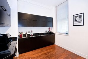 Cozinha moderna com bancada preta, armários embutidos e janela com persianas.