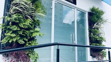 Entrada de hotel com porta de vidro, plantas em vasos de cada lado e um letreiro acima da porta.