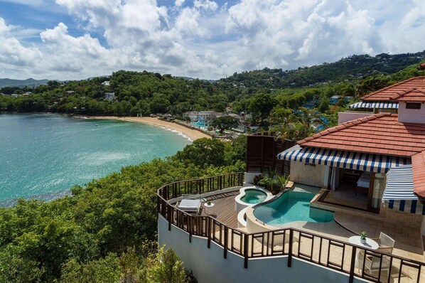 Resort com piscina particular, vista para a praia e paisagem verde exuberante.